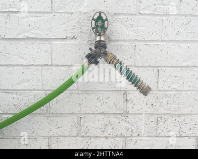 Closeup of a Frozen outdoor water spigot on white brick wall background ...