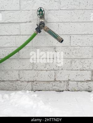Closeup of a Frozen outdoor water spigot on white brick wall background ...