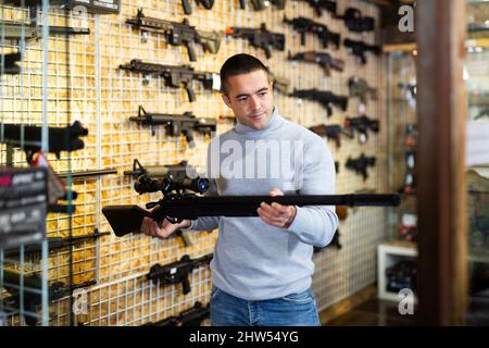 Man choosing sniper rifle in arms shop Stock Photo - Alamy