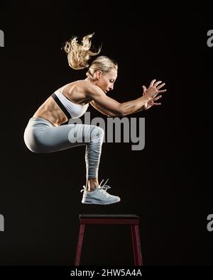 Athlete woman jumping over stool Stock Photo - Alamy