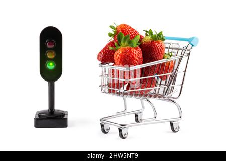 Fresh strawberries in a cart and a miniature traffic light isolated on ...