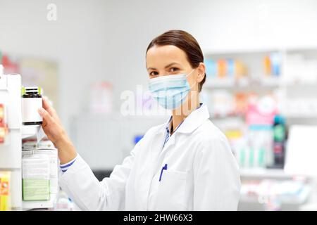 female apothecary in mask with drug at pharmacy Stock Photo - Alamy