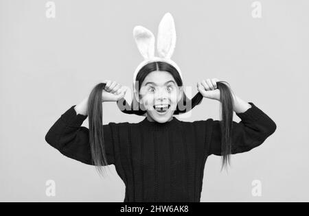 amazed easter child in bunny ears and bow tie on yellow background ...