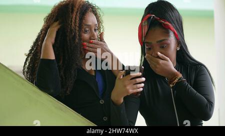 Mother and daughter reacting with shock to content online holding ...