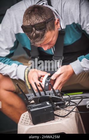 Behind the scenes. First assistant focus puller helps the cameraman ...