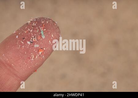 Close-up of microplastics lay on finger of human being. Small plastic ...