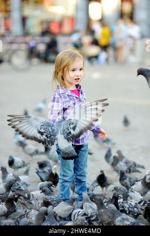 Cute little girl feeding and chasing birds on Dam Square in Amsterdam ...
