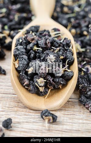 Black wolfberries or black goji berries, in a wooden bowl on table ...