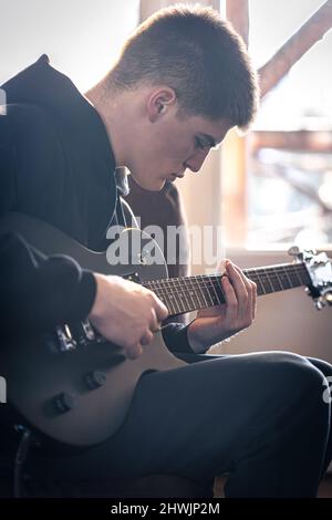 A young guy plays the electric guitar in his room Stock Photo - Alamy