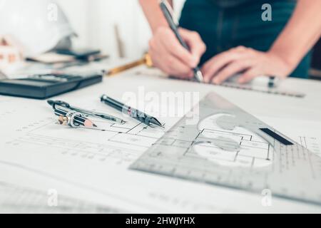 Architect engineer use pen, triangular angle ruler and compass on drawing design working on ...