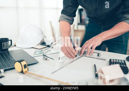 Architect engineer use pen and angle protector drawing design working on bueprint. House ...