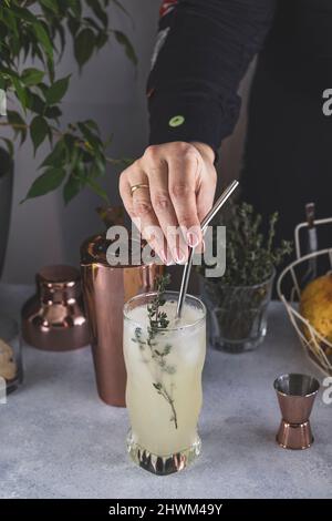 Real woman preparing Pear Collins Cocktail in highball glass or ...