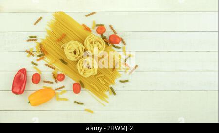 Raw pasta of various types and spices on a wooden table. View from ...