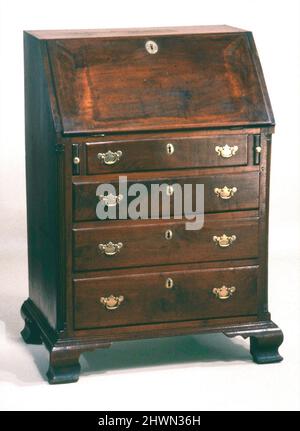 A vintage writing desk with a slanted top and ornate brass handles sits ...