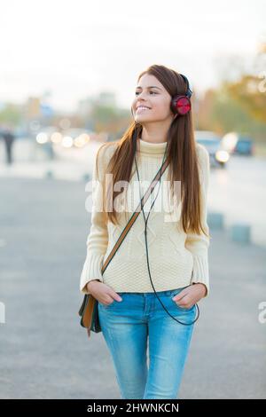 Happy woman listening music through headphones while using laptop in ...