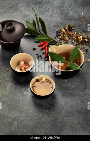 Asian tea set on dark background. Plant leaves, natural herbal tea ...