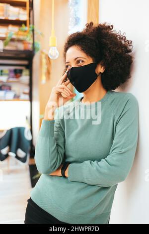 Hispanic businesswoman in face mask sitting in office Stock Photo - Alamy