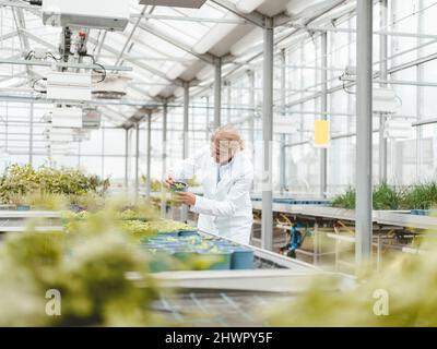 scientist doing research on plants holding a green solution in a test ...