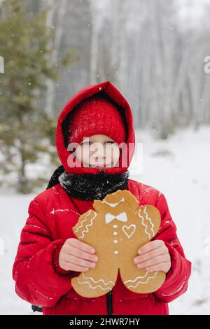 The boy is holding a gingerbread cookie in the shape of a snowman ...