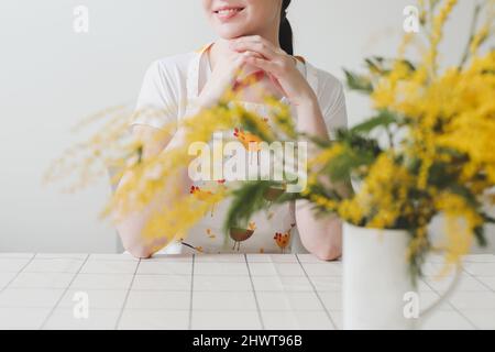 Beautiful young woman with bouquet of mimosa flowers on brown ...
