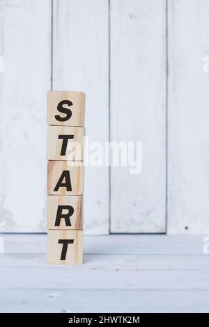 The word Start on wooden cube push button on blue and white background ...
