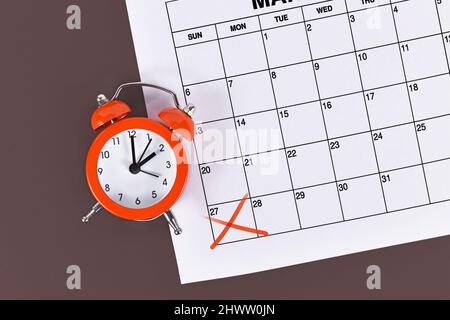 March and alarm clock on blue background Stock Photo - Alamy