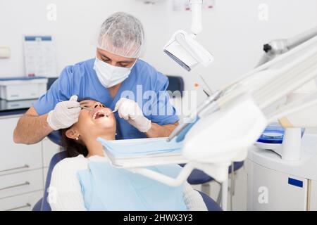 Dentist man examining a latin female patient teeth Stock Photo - Alamy