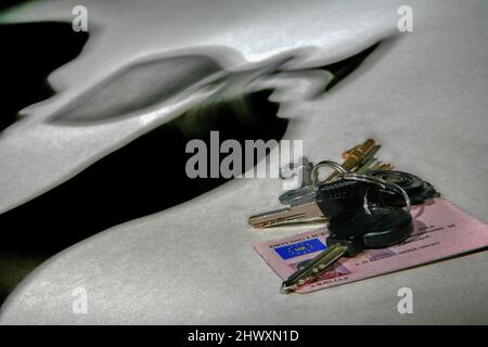 The shadow of a man drinking alcohol with his driving licence and car ...
