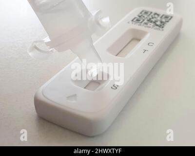 A covid swab sample in buffer solution is dropped onto the test ...