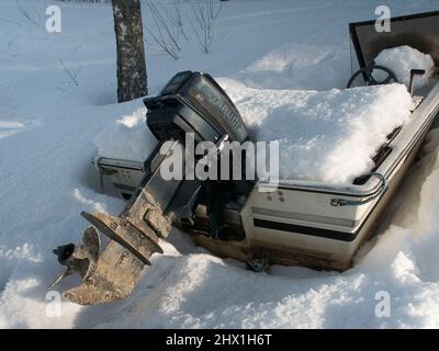 boat with outboard motor covered with snow in winter at the boat ...