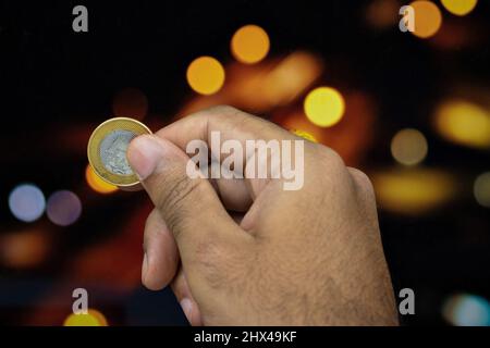 Holding a Brazilian money coin at a blurry lights background Stock ...