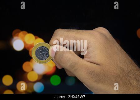 Holding a Brazilian money coin at a blurry lights background Stock ...