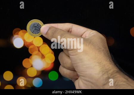 Holding a Brazilian money coin at a blurry lights background Stock ...