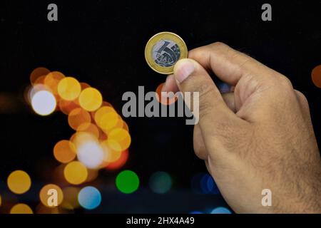 Holding a Brazilian money coin at a blurry lights background Stock ...