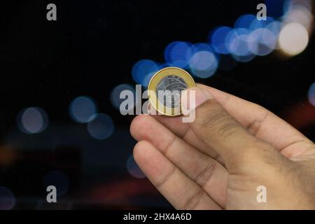 Holding a Brazilian money coin at a blurry lights background Stock ...
