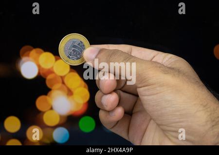 Holding a Brazilian money coin at a blurry lights background Stock ...