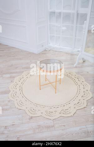 A knitted cotton rug and a decorative round table lie on the floor ...