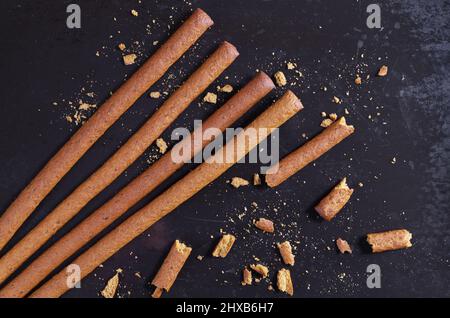 Bread sticks whole and broken on old black metal background, top view ...