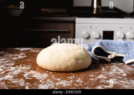 The finished kneaded round dough lies on the kitchen table at home ...