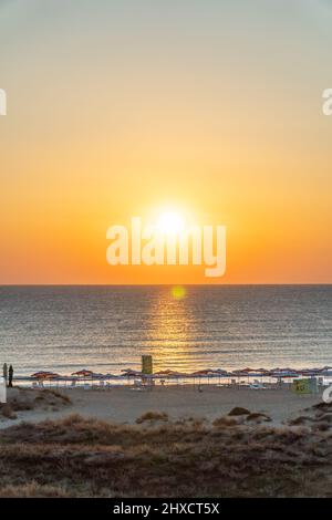 Amazing sunrise over the sand dunes on the shore with sun beds and ...