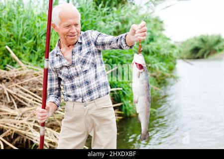 Fisherman pulling fish from river Stock Photo - Alamy