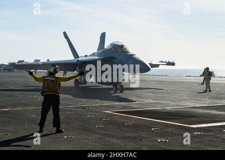 Sailor directs an E/A-18G Growler on the flight deck of the aircraft carrier USS Nimitz Stock ...