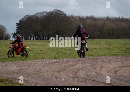 a pair of motor cyclists (bikers) riding off-road motorbikes across ...