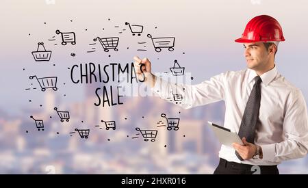 Young businessman with helmet drawing sale sign Stock Photo - Alamy