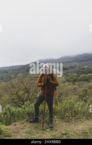 Vertical shot of the Caucasian male hiking in the forest and taking ...