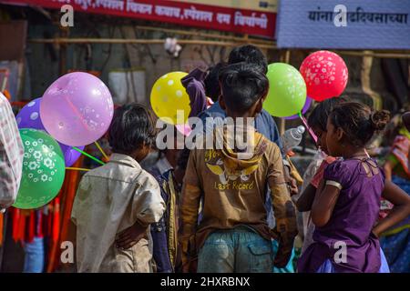 Indian poor kids selling colorful balloons in the crowded market area ...