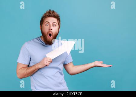 Portrait of bearded man holding arrow pointing up looking at camera ...