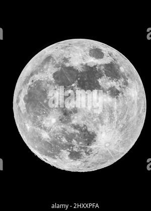 A vertical grayscale of the full moon with stars shining in the ...