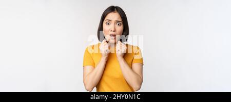 Portrait of scared asian woman shaking from fear, looking terrified and ...