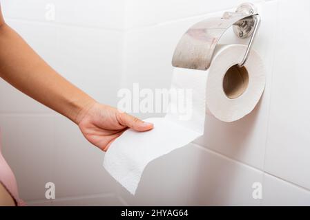 woman sitting on toilet and pulling a paper tissue Stock Photo - Alamy
